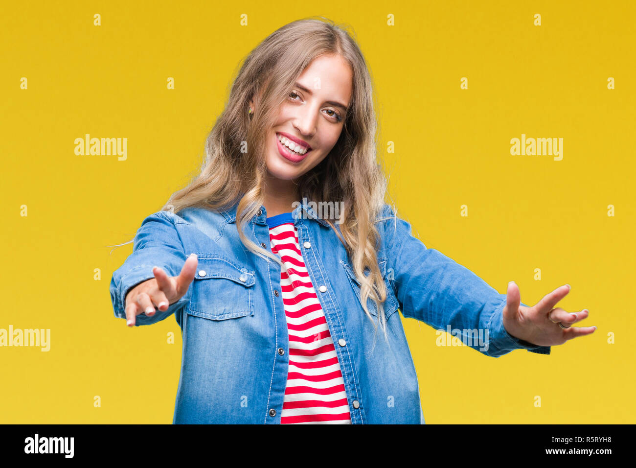 Beautiful young blonde woman over isolated background looking at the ...