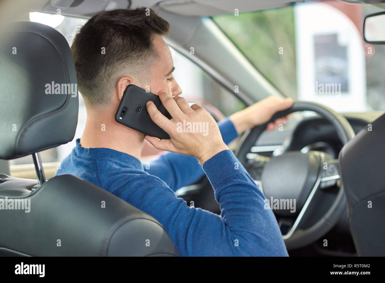Back view of young man driving car. Attractive guy in blue sweater ...