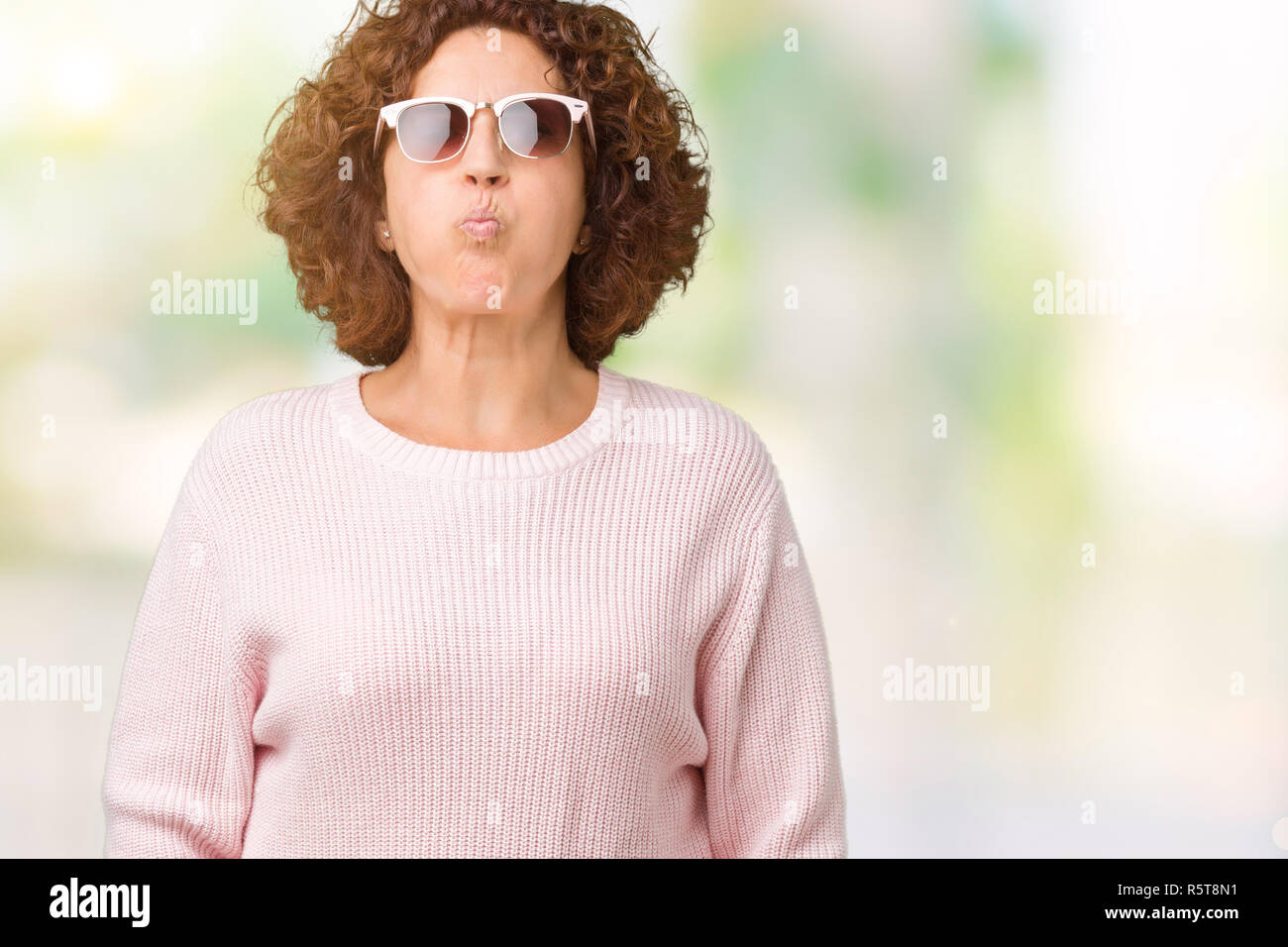 Beautiful middle ager senior woman wearing pink sweater and sunglasses ...