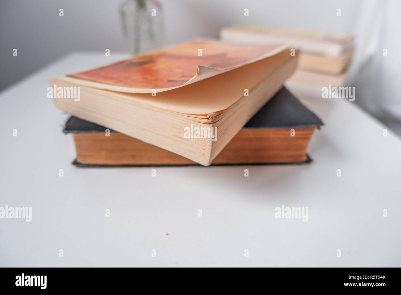 An old dog eared used paperback book on a table in a white interior ...