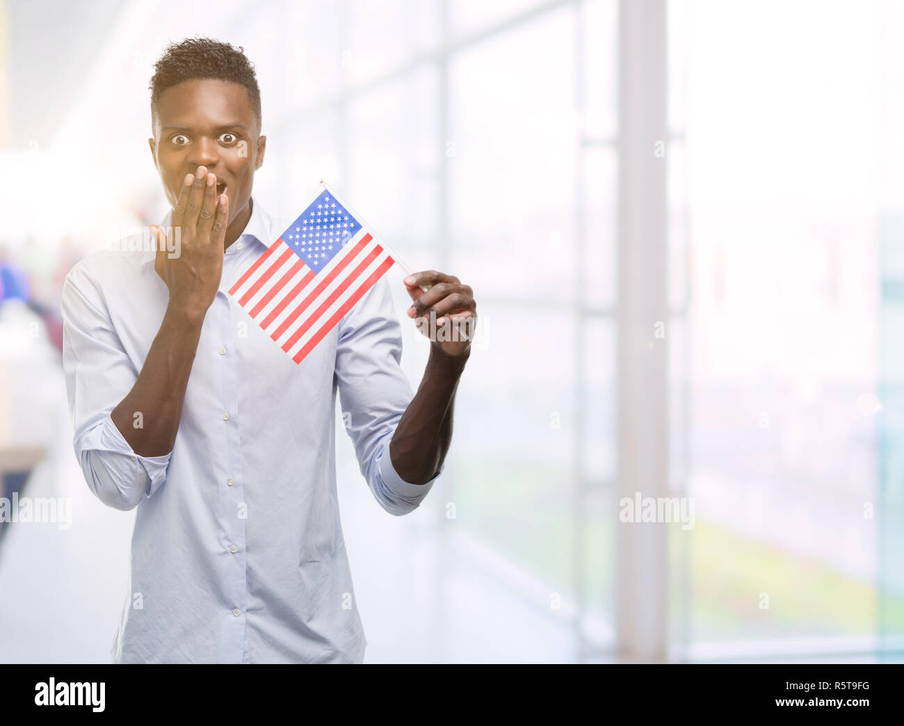 Young african american man holding USA flag cover mouth with hand ...