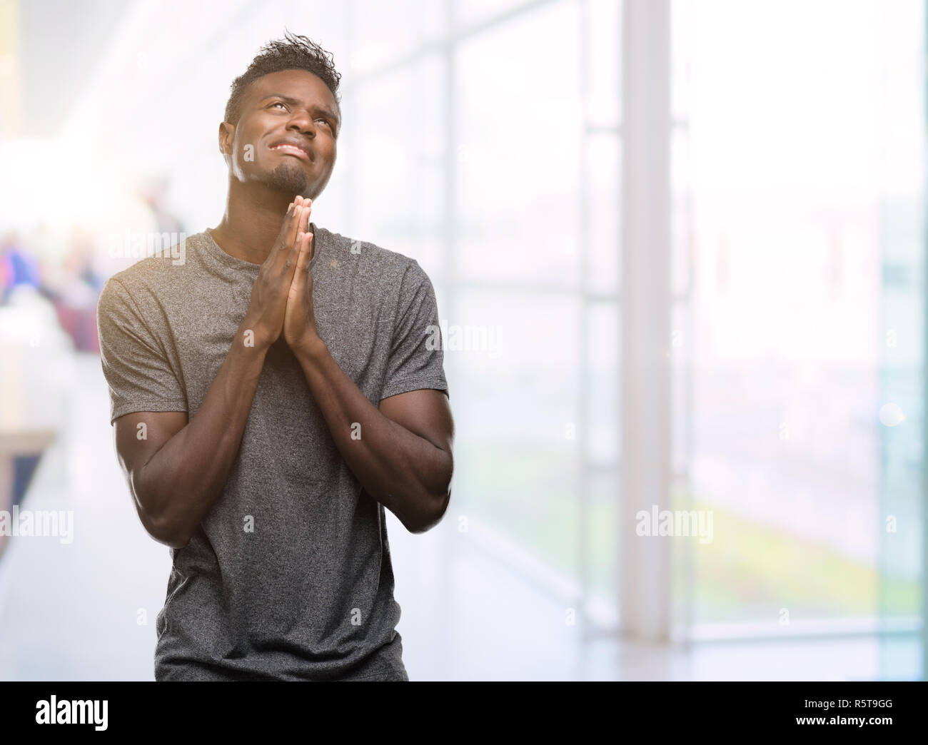 Young african american man wearing grey t-shirt begging and praying ...