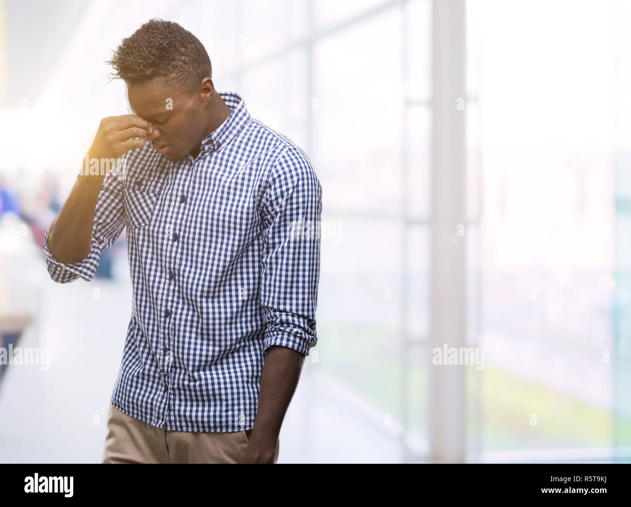 Young african american man wearing blue shirt tired rubbing nose and ...