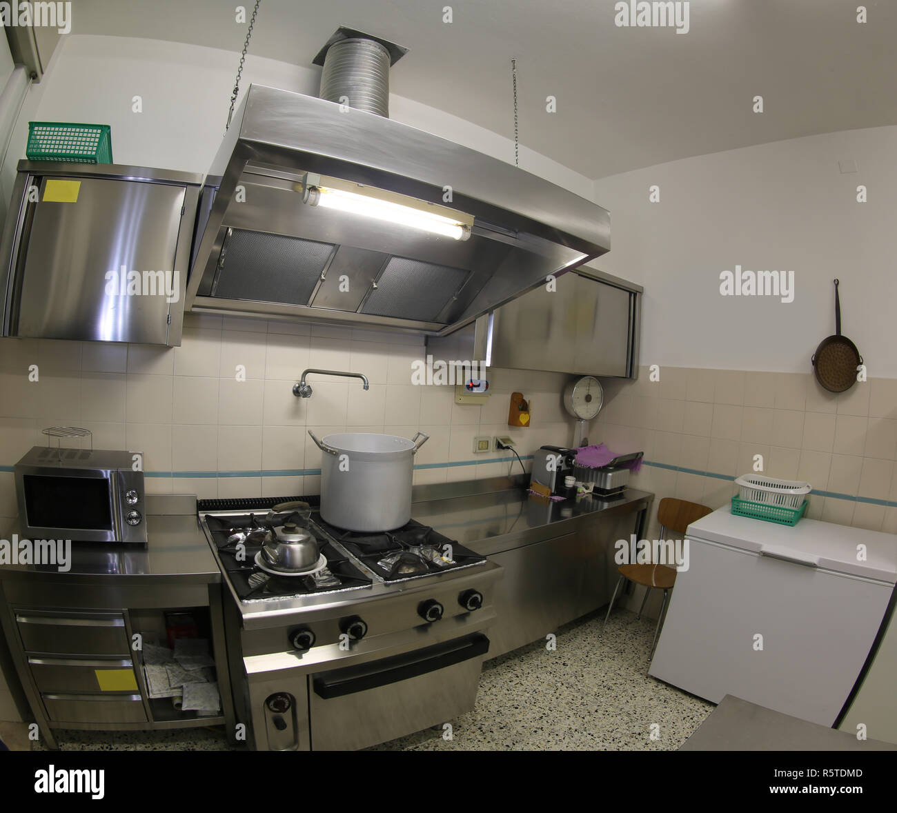 large industrial kitchen with steel stoves and a giant aluminum pot ...