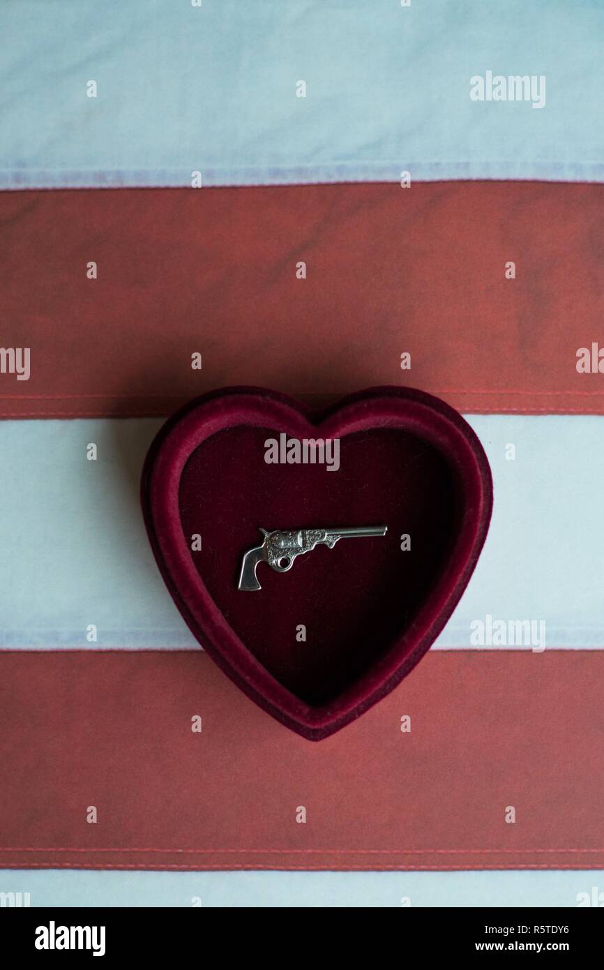A mini silver gun in a heart shaped box against an American flag Stock ...