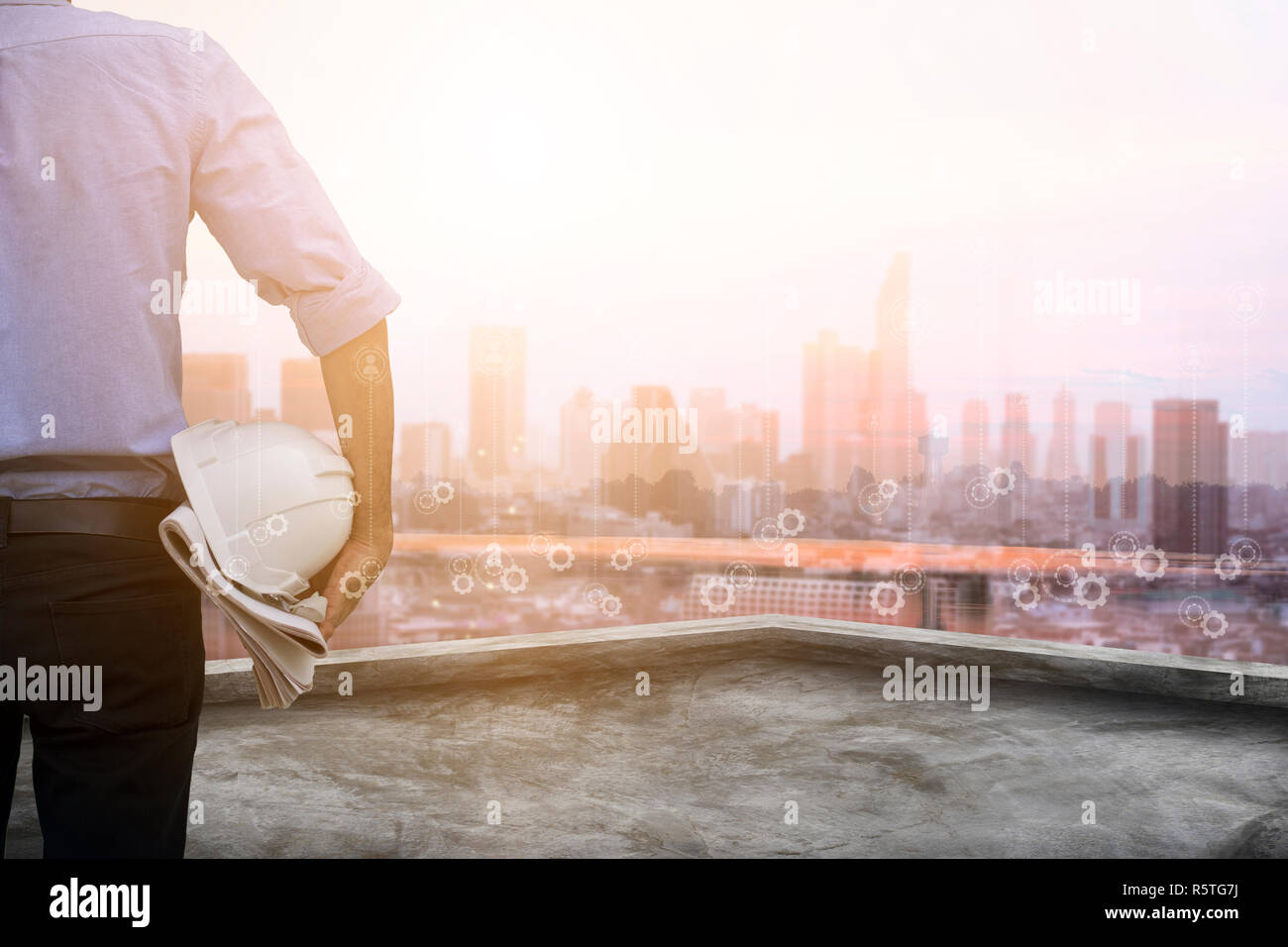 engineer holding helmet and standing on roof top of building and ...