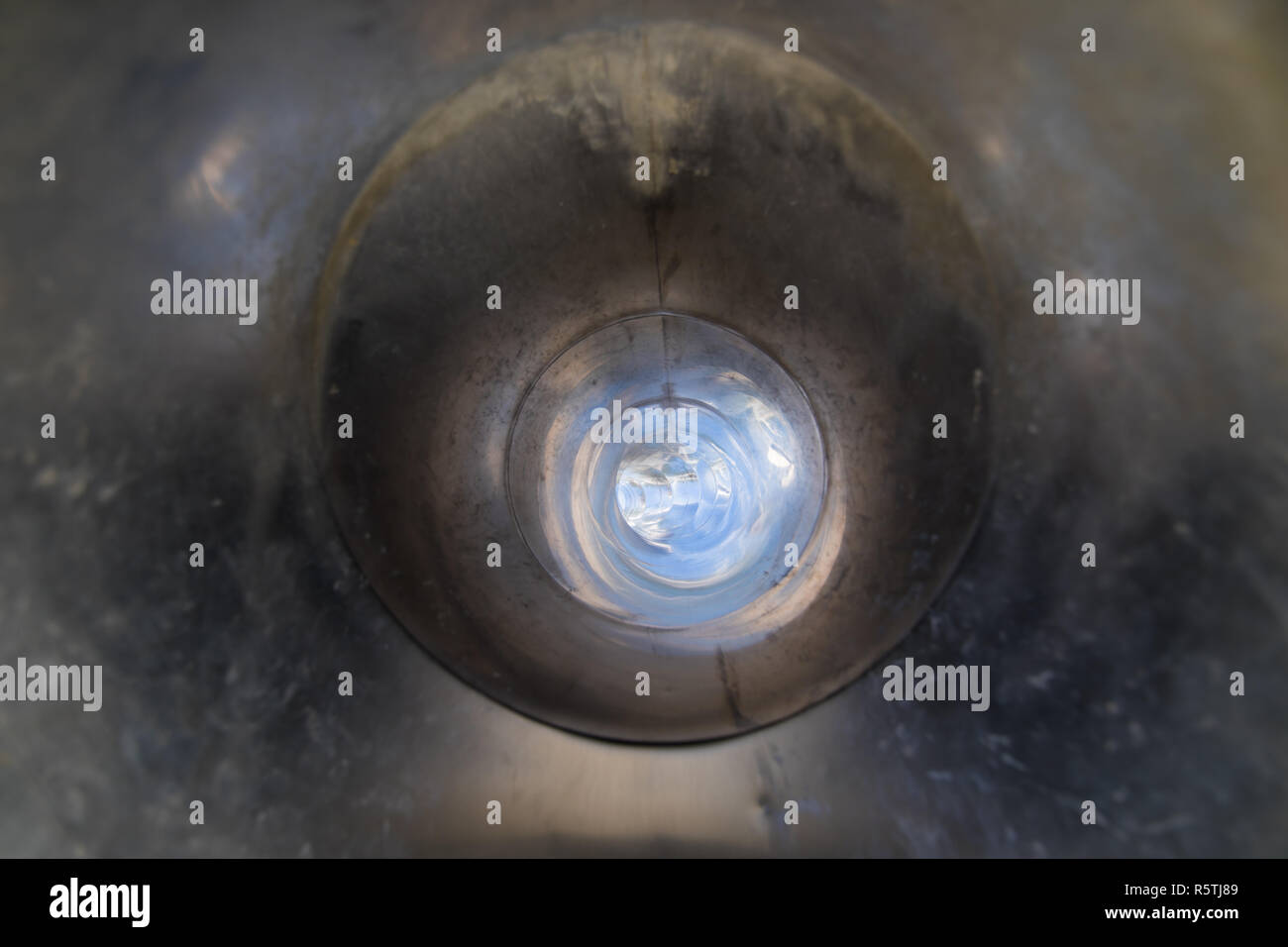 inside tube or pipe of great metal slide in playground with light at ...