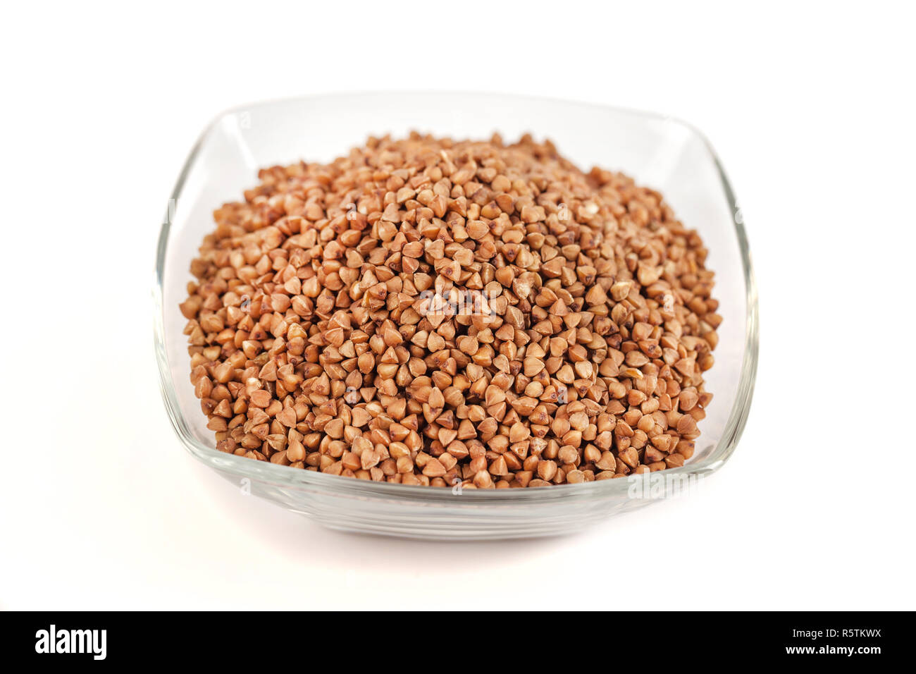 Roasted buckwheat grains in glass bowl isolated on white background ...