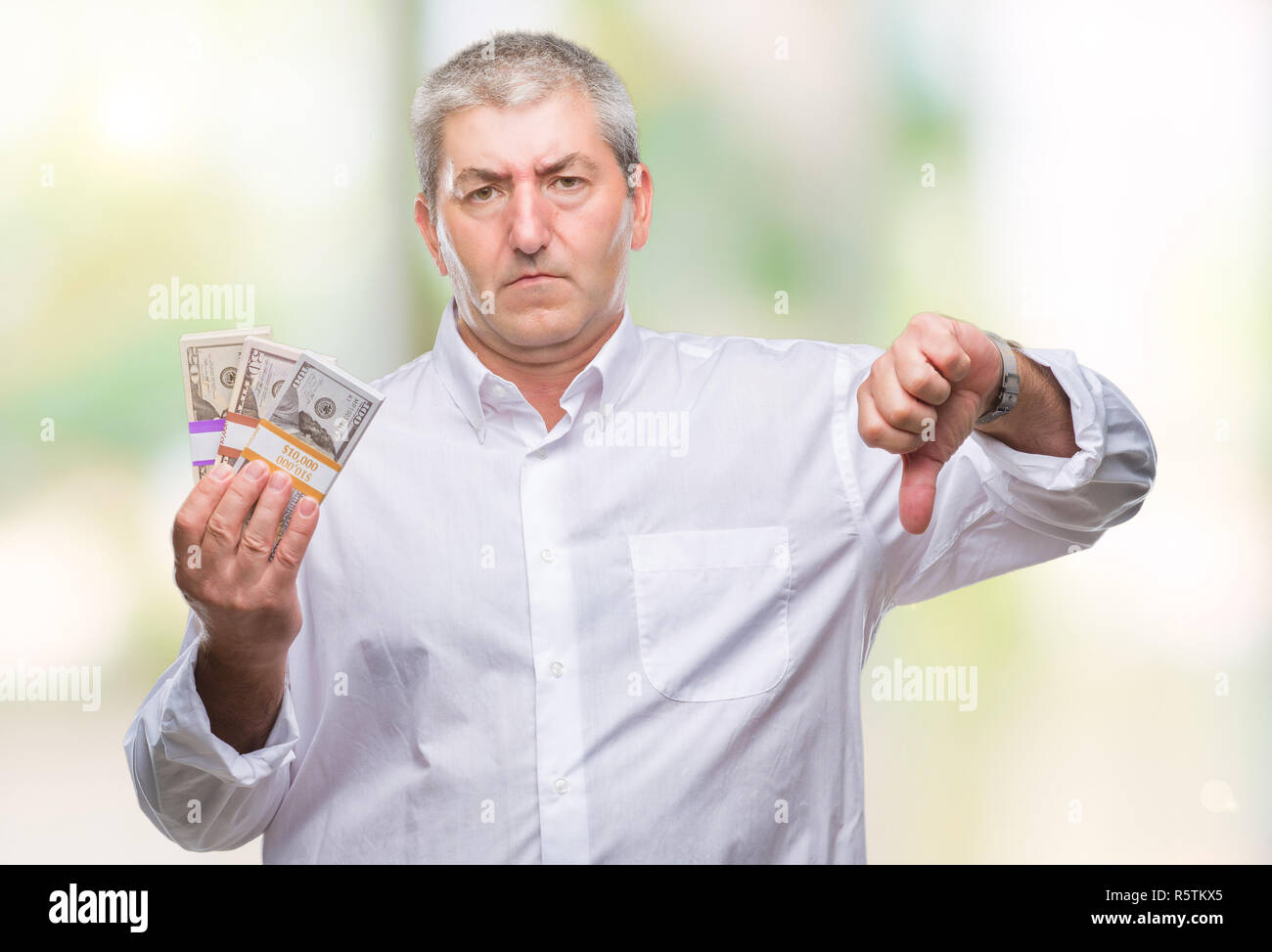 Handsome senior man holding bunch of money over isolated background ...