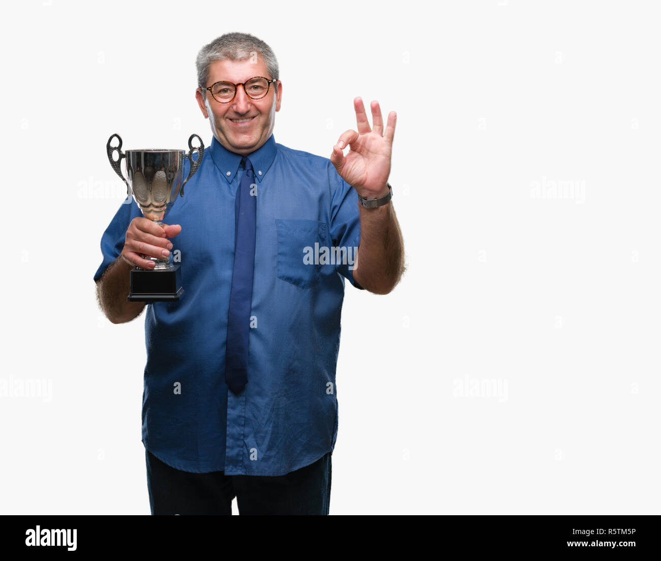 Handsome senior successful man holding trophy over isolated background ...