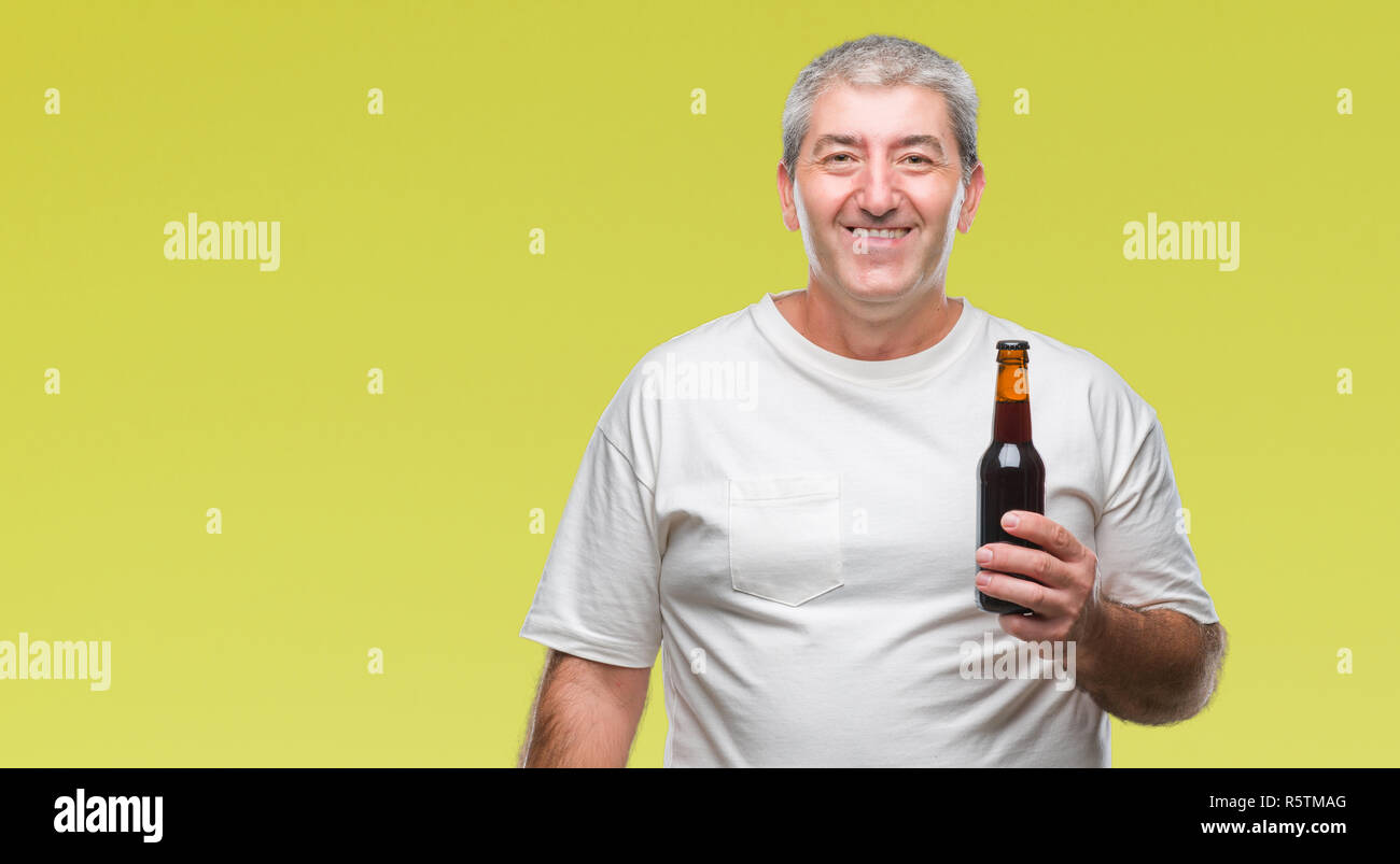 Handsome senior man drinking beer bottle over isolated background with ...