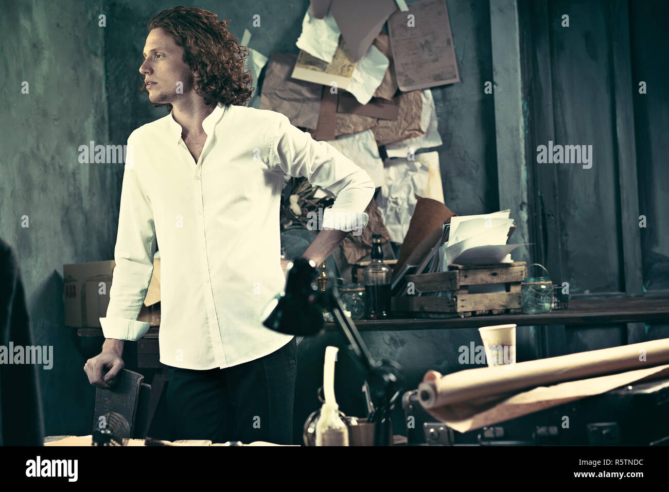 Writer at work. Handsome young writer standing near the table and ...