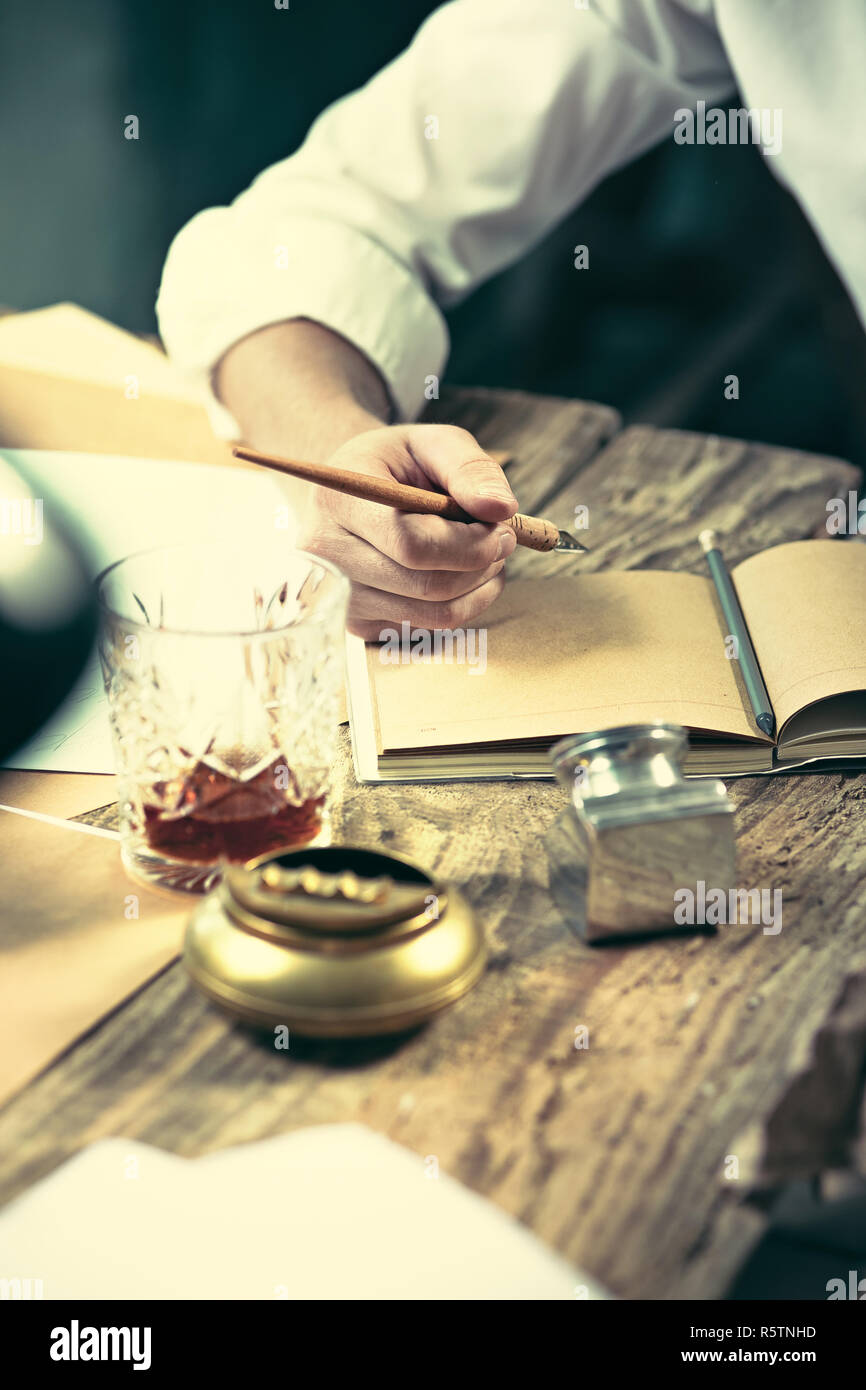 Writer at work. Handsome young writer sitting at the table and writing ...