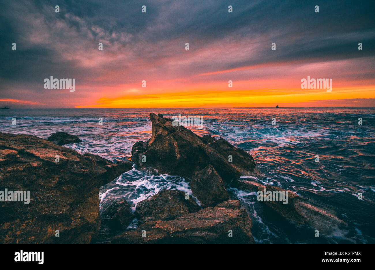 Sunset at the beach with rocks and waves Stock Photo - Alamy