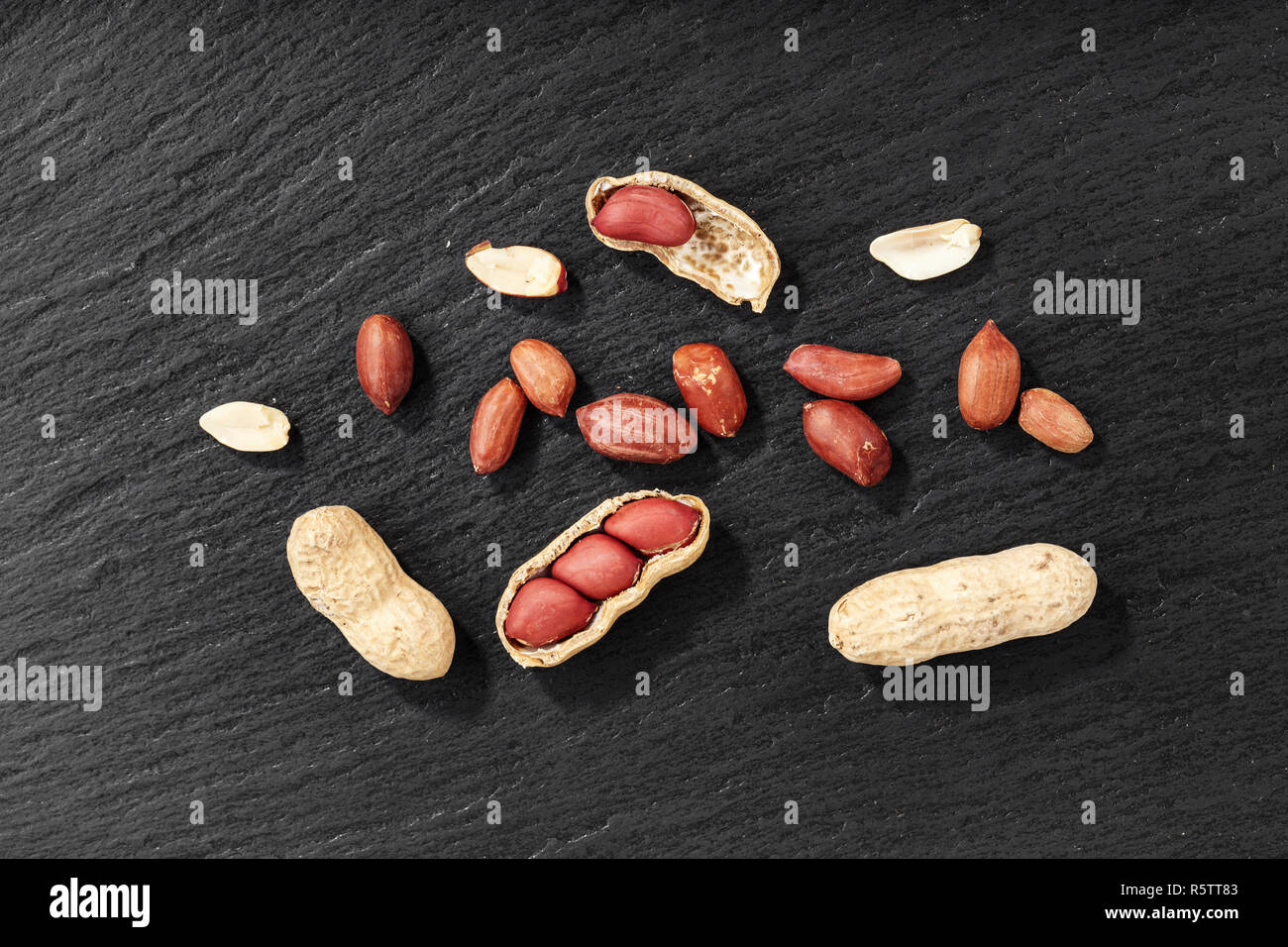 raw peeled peanuts scattered on a black background. space for text ...
