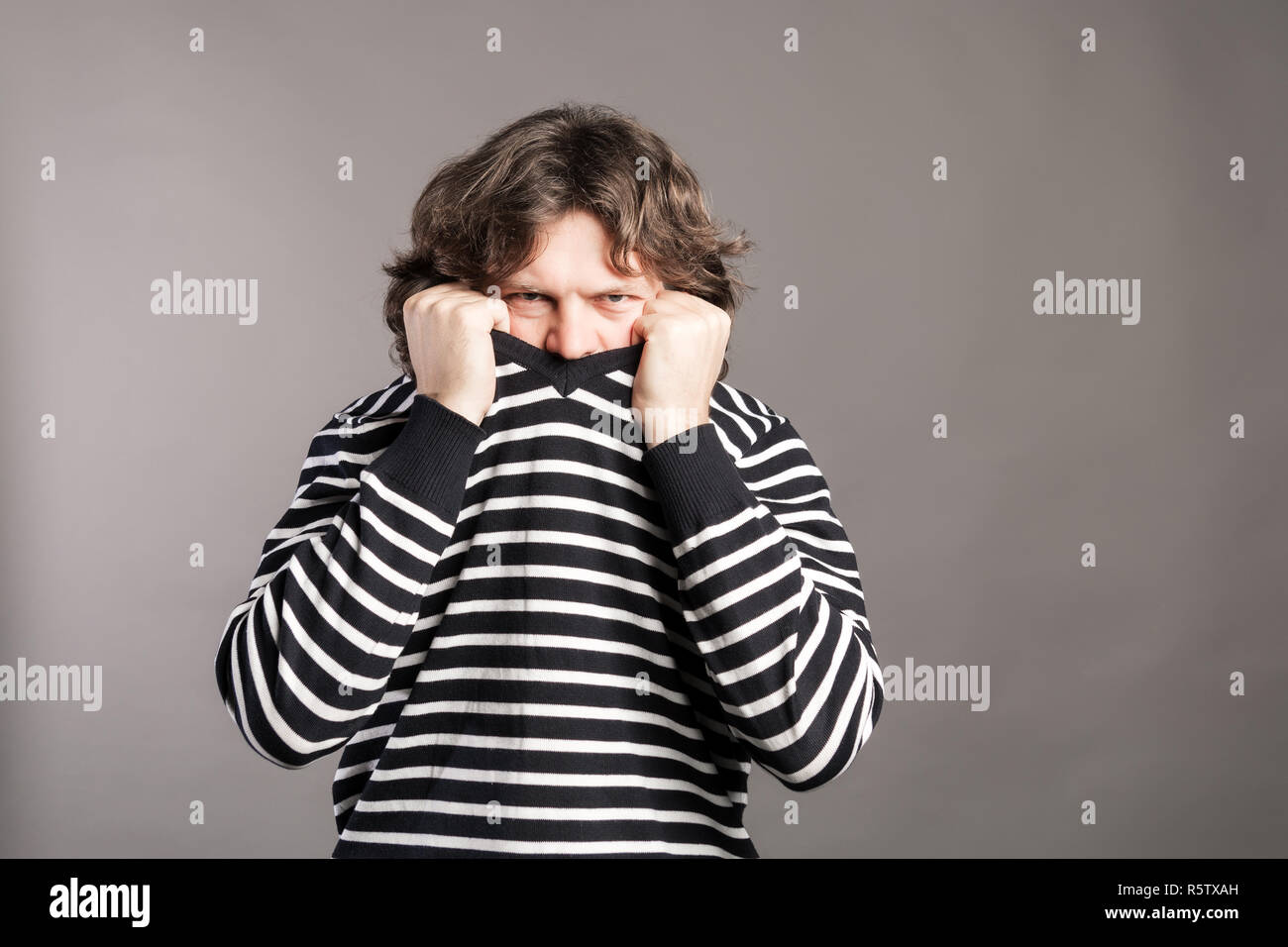 Young man pulling black and white striped sweater over head against ...