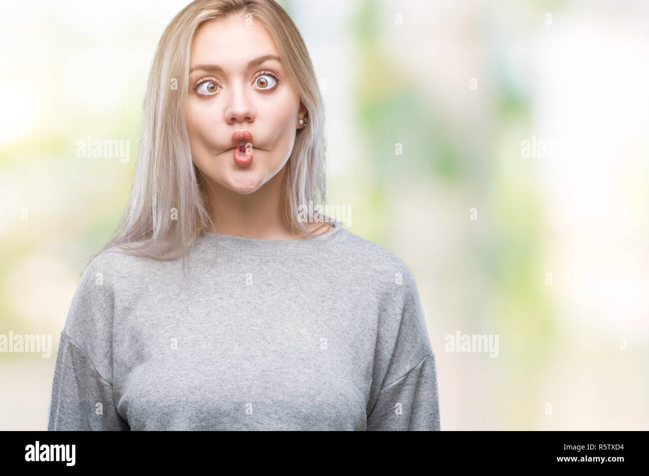 Young blonde woman over isolated background making fish face with lips ...