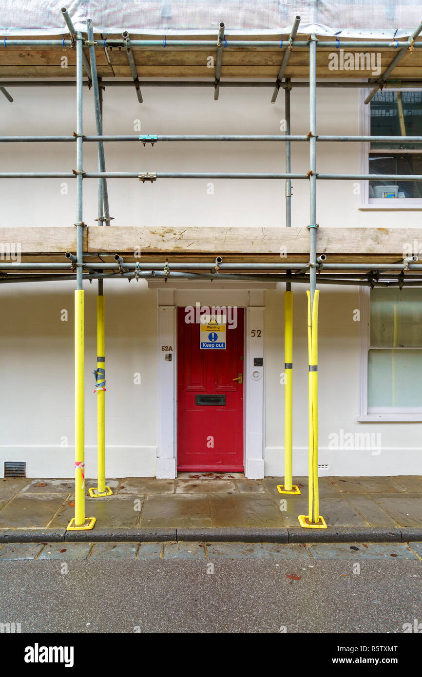 Builders scaffolding above door with warning sign and pavement Stock ...