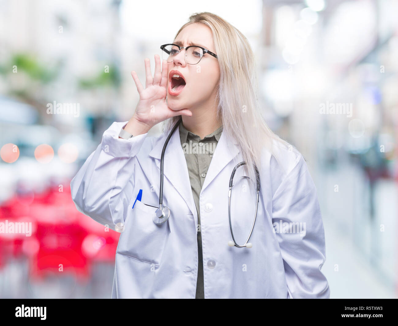 Young blonde doctor woman over isolated background shouting and ...