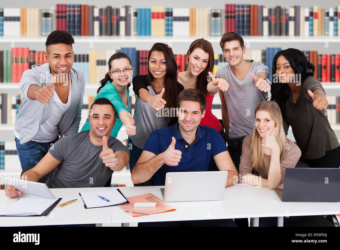 College Students Gesturing Thumbs Up Sign Together Stock Photo - Alamy
