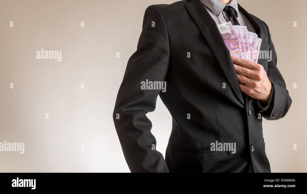 Businessman placing Euro bills in the inner pocket of his jacket over ...