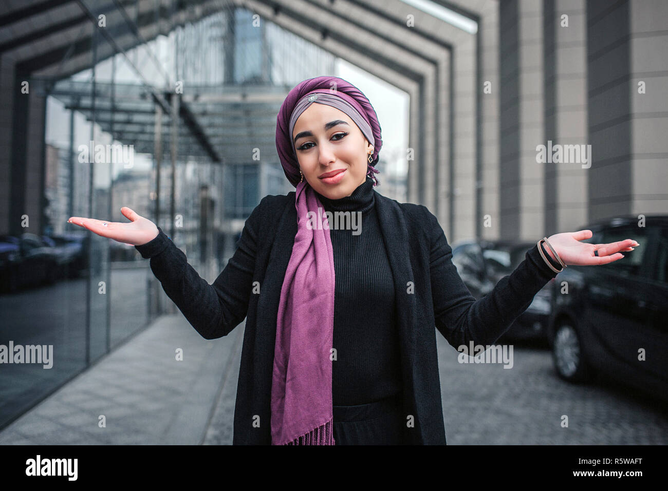 Happy arabian woman stand outside and look on camera. She holds hands ...