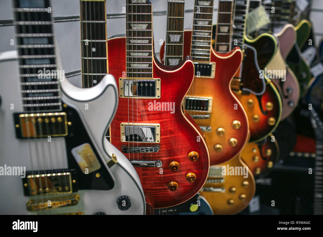 Picture of many electronic guitars hanging. They are different colors ...