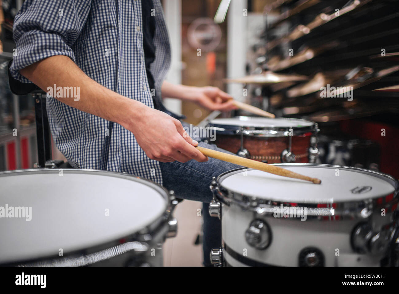 Picture of young bearded man playing on drus. He touches them with ...