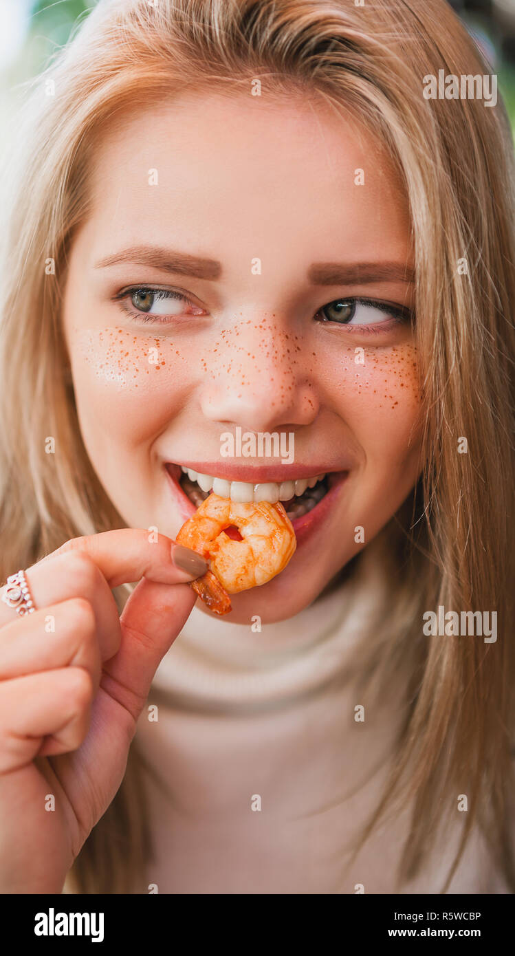 Young beautiful woman eating black pasta with seafood and cuttlefish ...