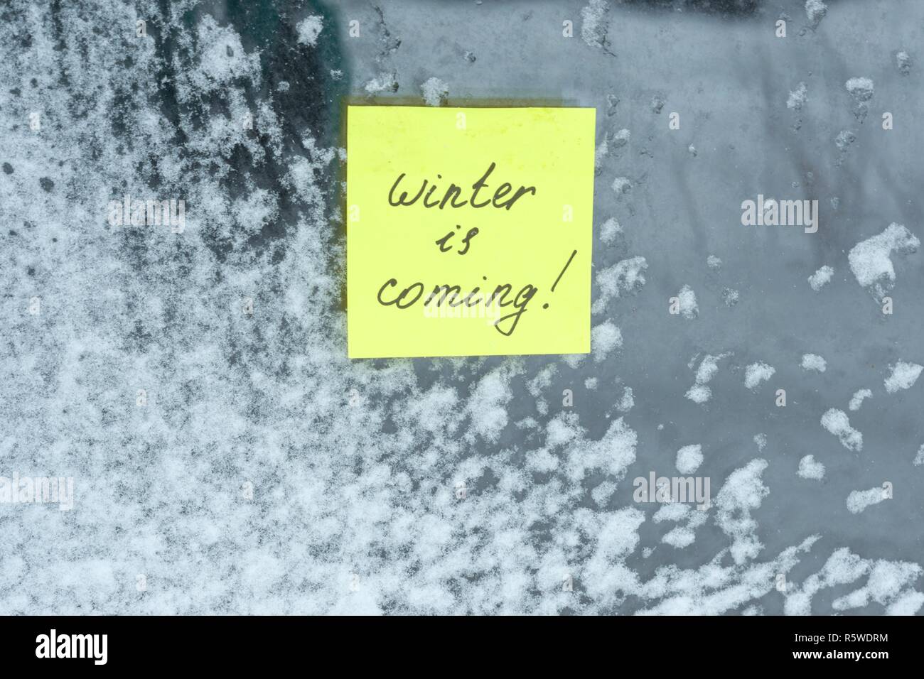 Winter is coming, texture background snow-covered window with a sticker ...