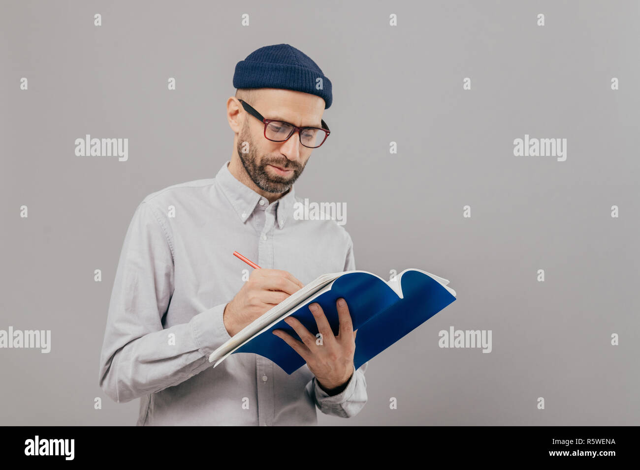Serious male teacher writes down notes for next class, holds notepad ... Serious male teacher writes down notes for next class, holds notepad ...