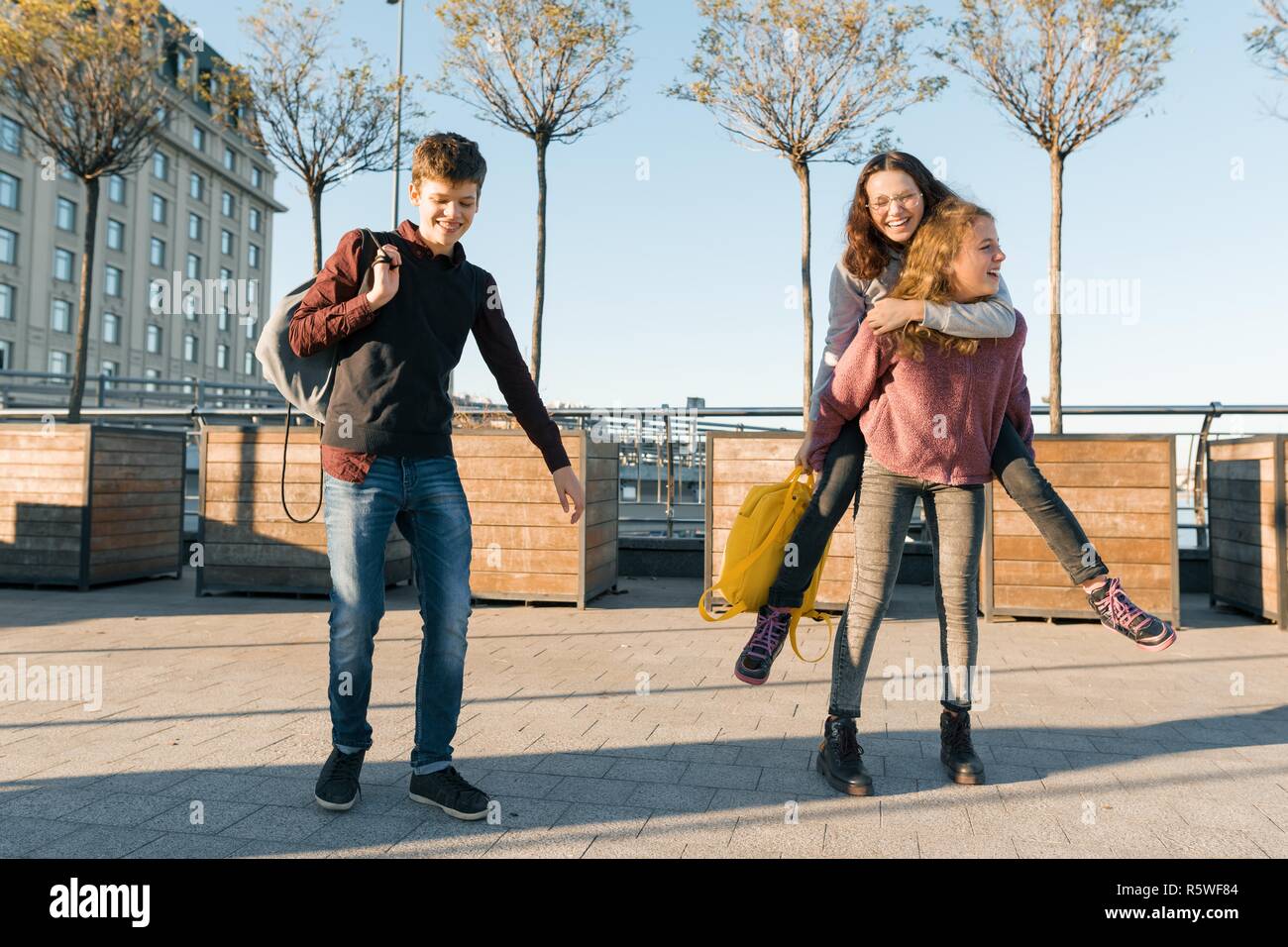 Friends teenagers students with school bags, having fun on the way from ...