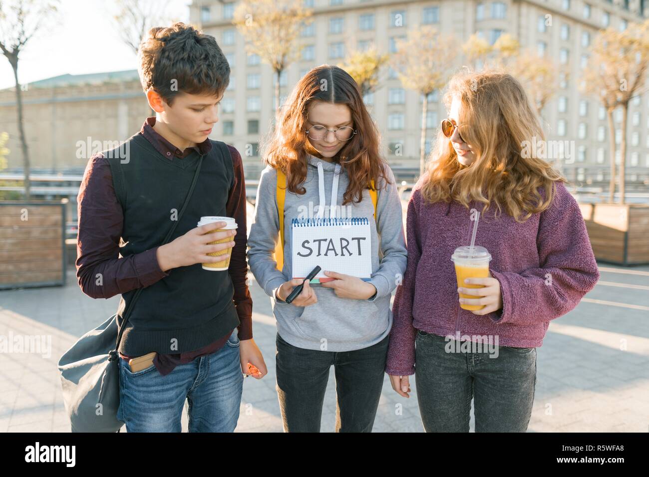 Group teenagers boy and two girls, with a notepad with handwritten word ...