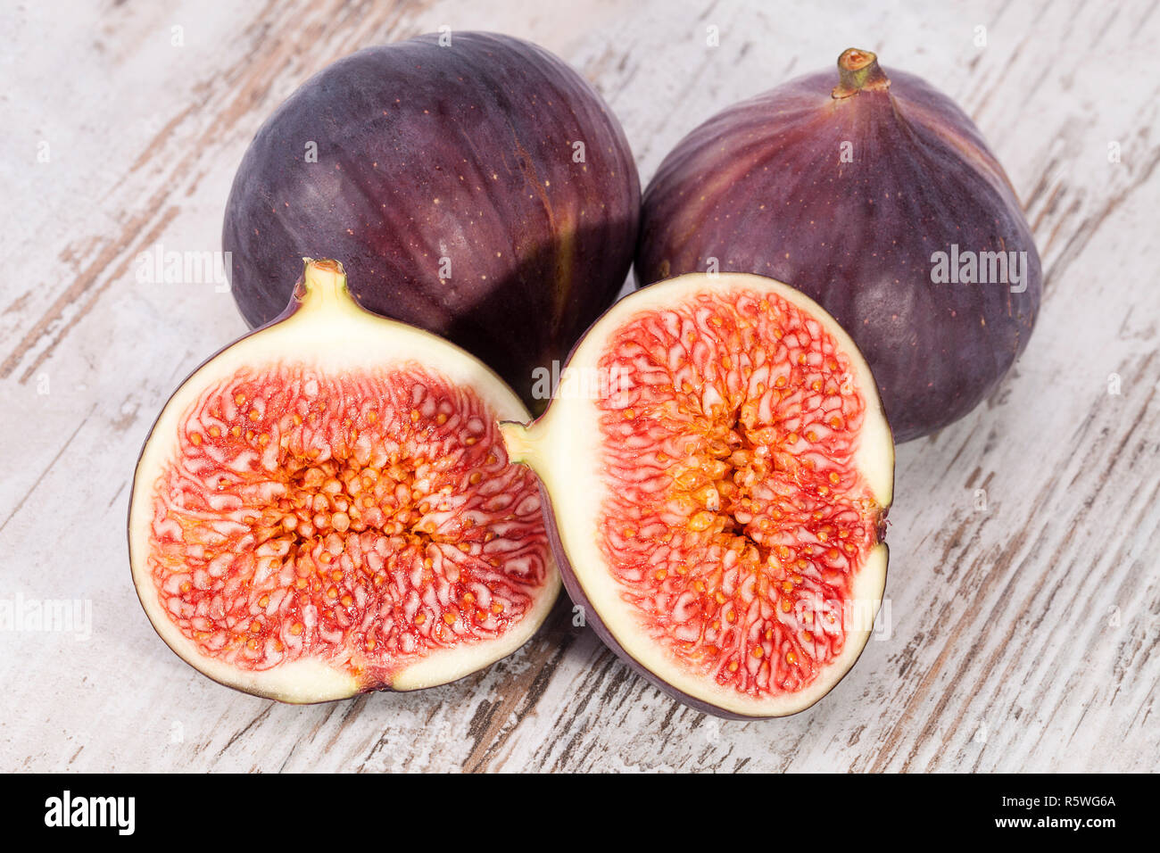 Fruits of whole and half fresh figs on wooden plank, close up Stock ...
