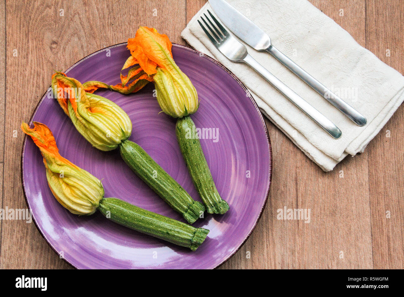plate of courgettes with their flower on a wood table Stock Photo - Alamy