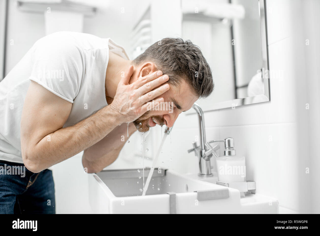 Man washing his face with fresh water and foam in the sink at the white bathroom Stock Photo - Alamy