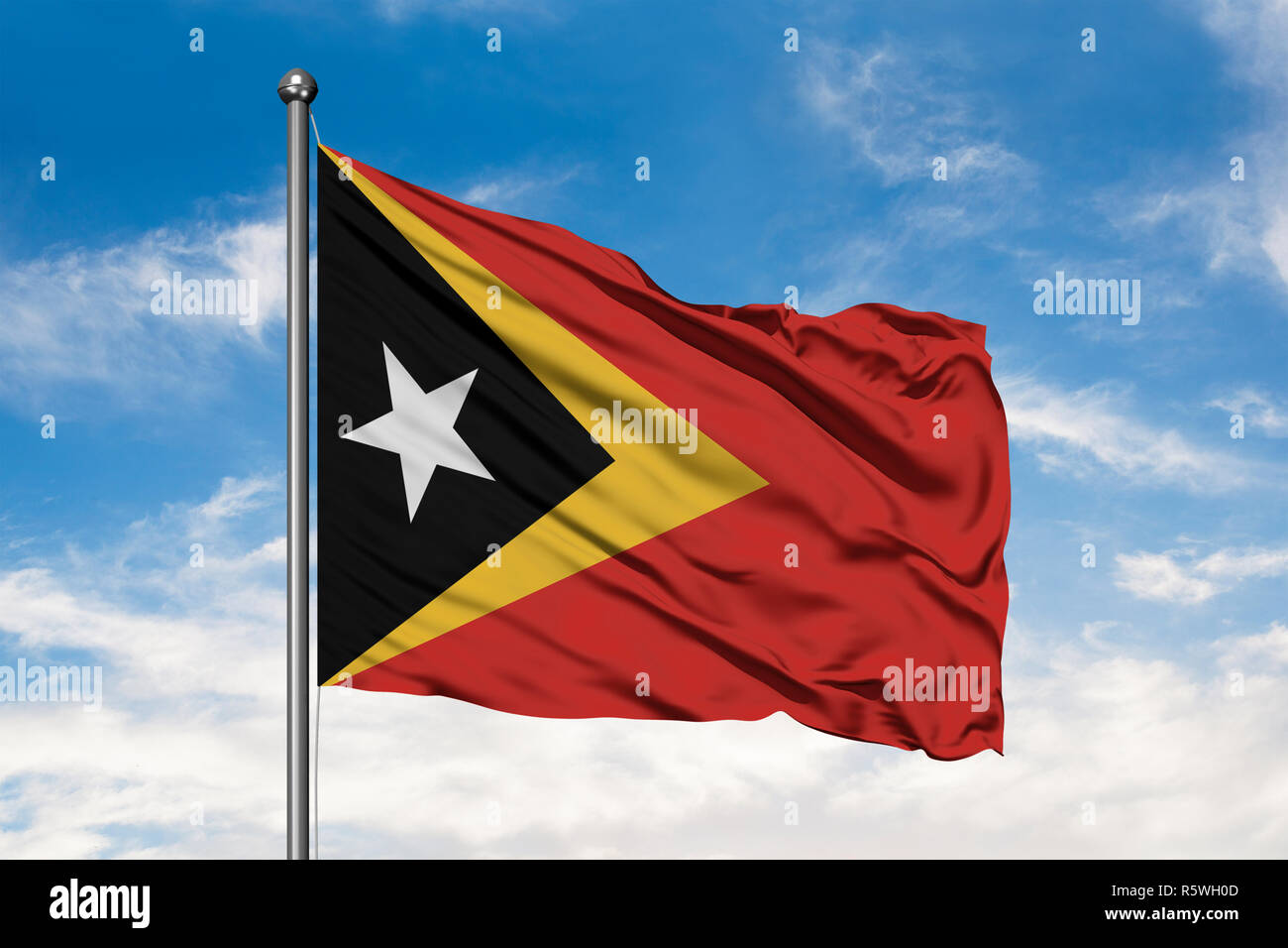 Flag of East Timor waving in the wind against white cloudy blue sky ...
