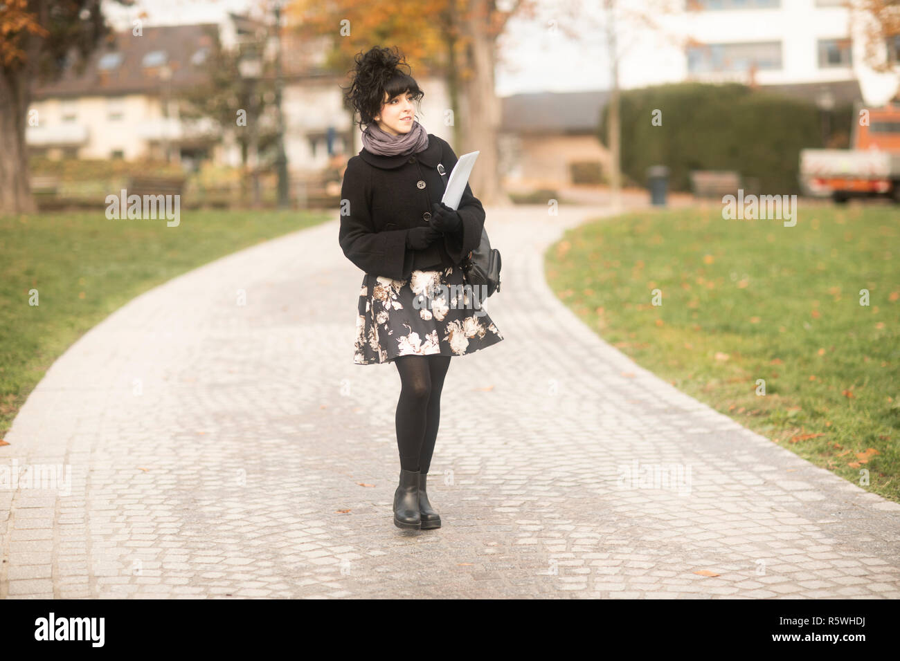 Woman walking along a footpath carrying paperwork, Germany Stock Photo ...