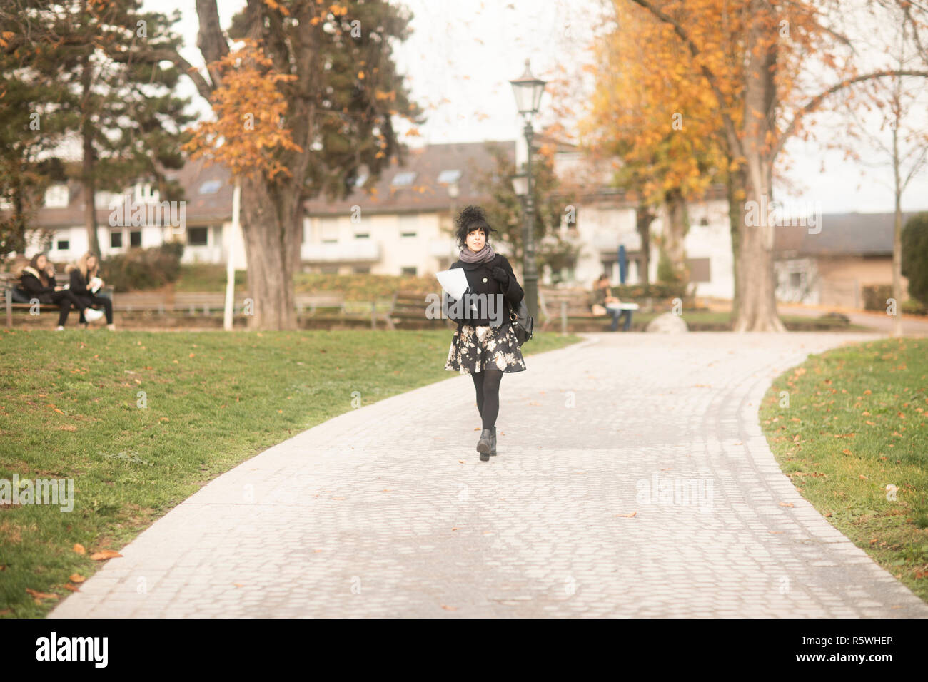 Woman walking along a footpath carrying paperwork, Germany Stock Photo ...