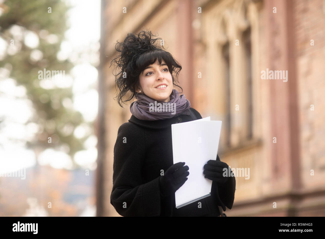Woman walking along a footpath carrying paperwork, Germany Stock Photo ...