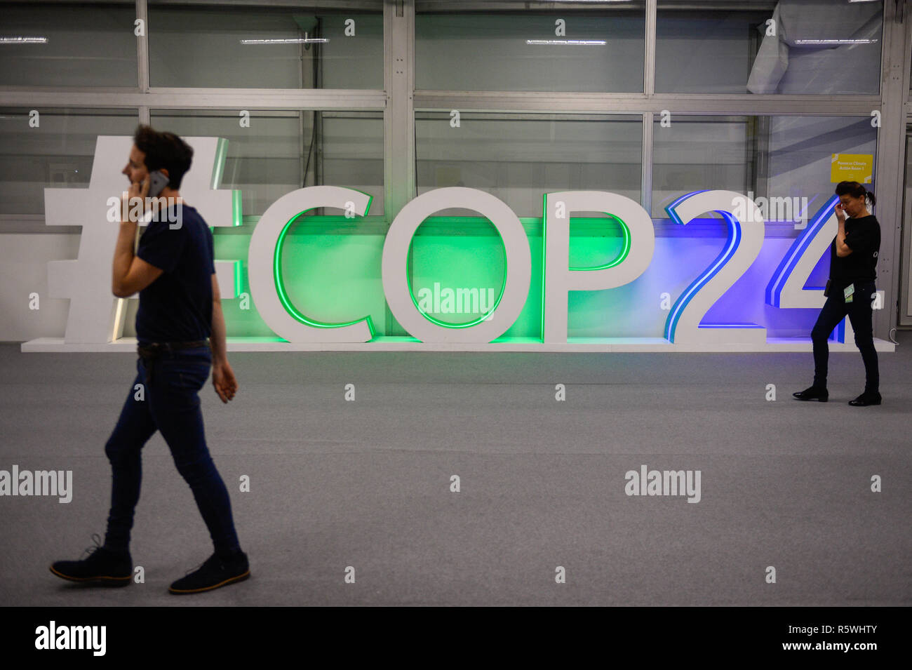 People are seen walking past a sign saying "COP 24" during the COP24 UN ...