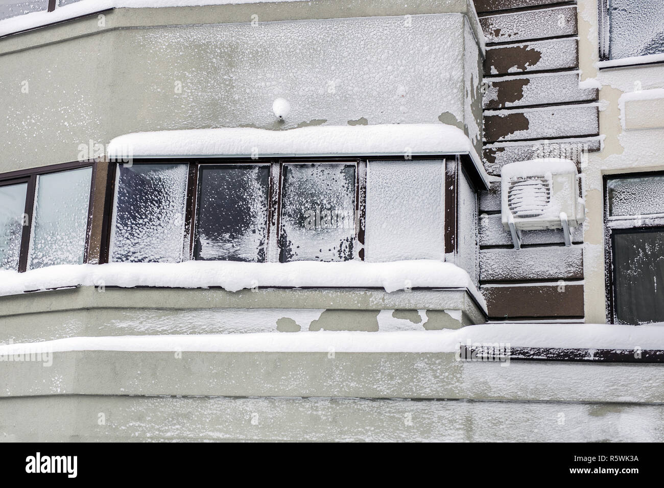 Building facade of modern high-rise apartment house covered with snow ...