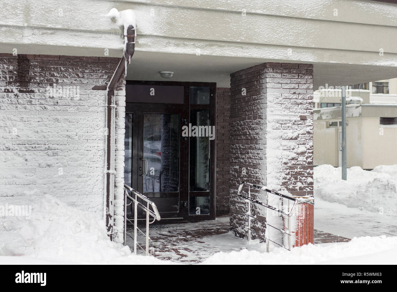 Entrance of modern high-rise apartment building covered with snow and ...