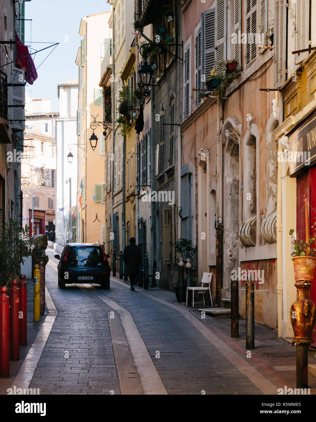 Car driving away down a narrow alley with classic facades in Marseille ...