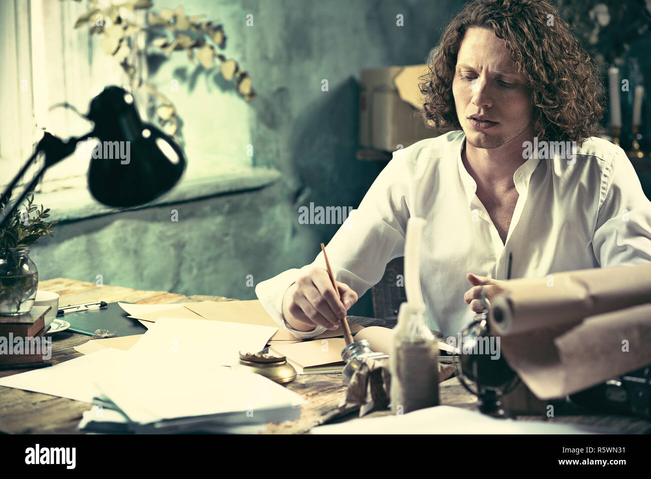 Writer at work. Handsome young writer sitting at the table and writing ...