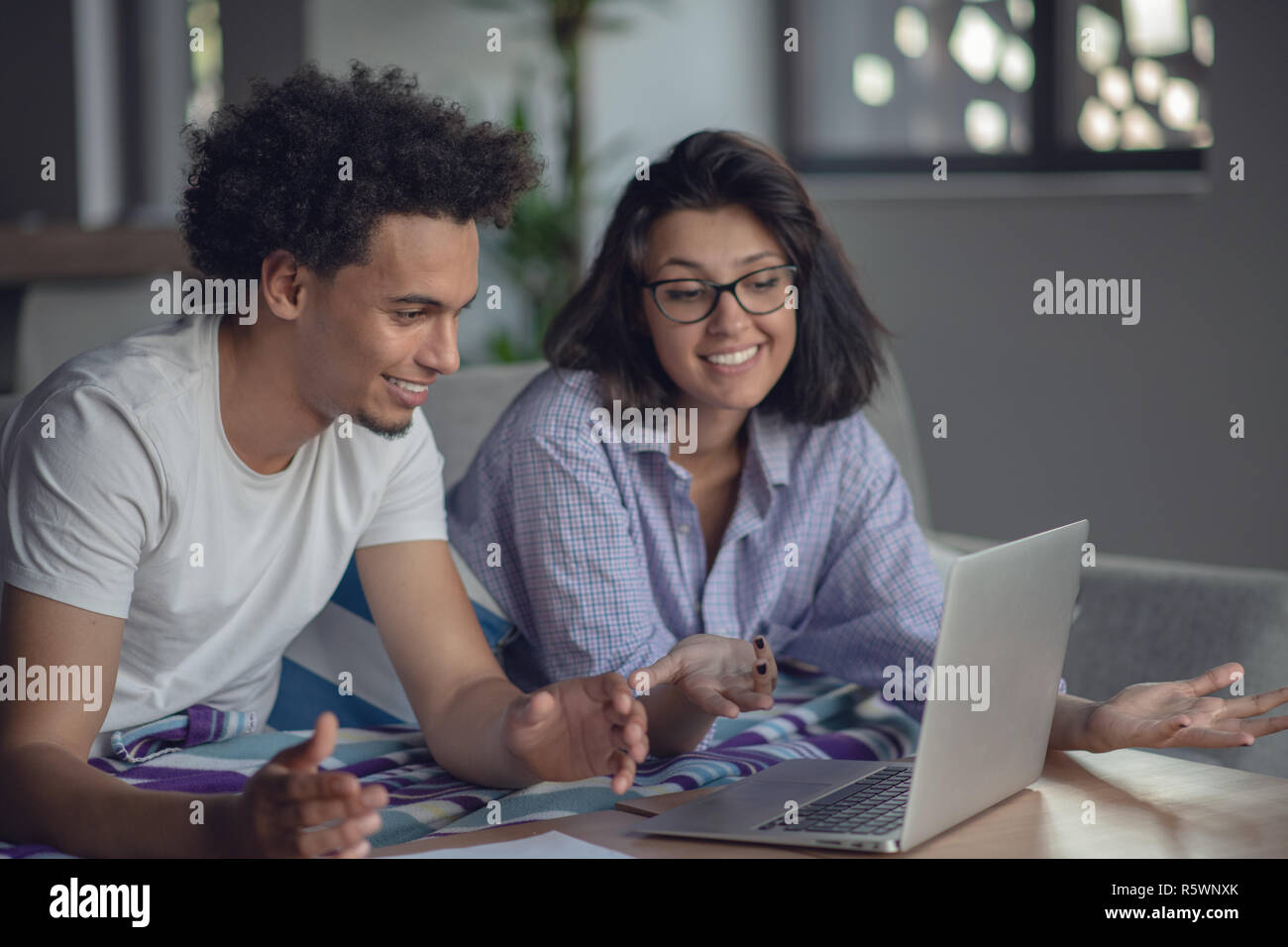 Young attractive diverse couple browsing internet, using laptop ...