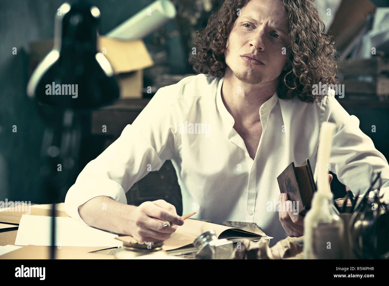 Writer at work. Handsome young writer sitting at the table and writing ...
