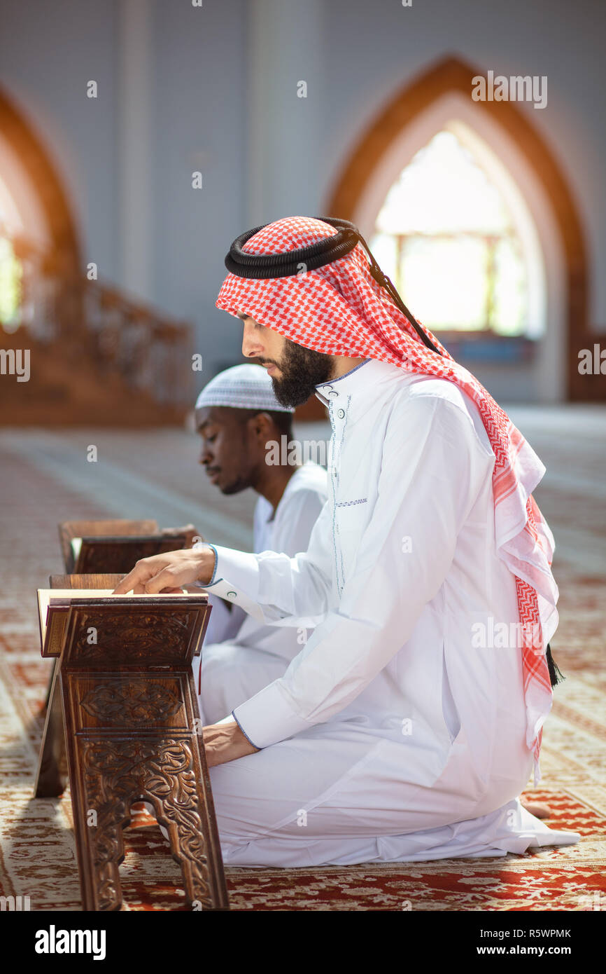 Muslim men praying with holy books in mosque Stock Photo - Alamy