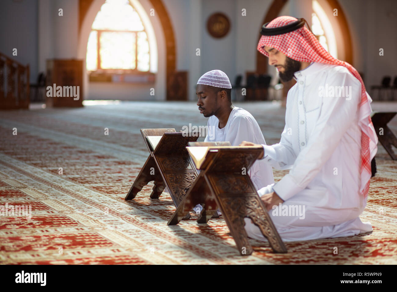 Muslim men praying with holy books in mosque Stock Photo - Alamy
