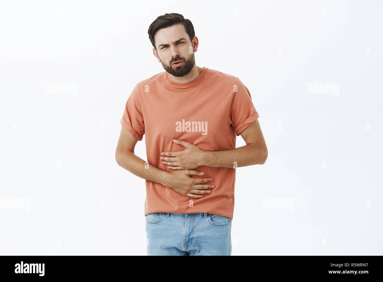 Man feeling discomfort in stomach eating fast food, holding hands on ...